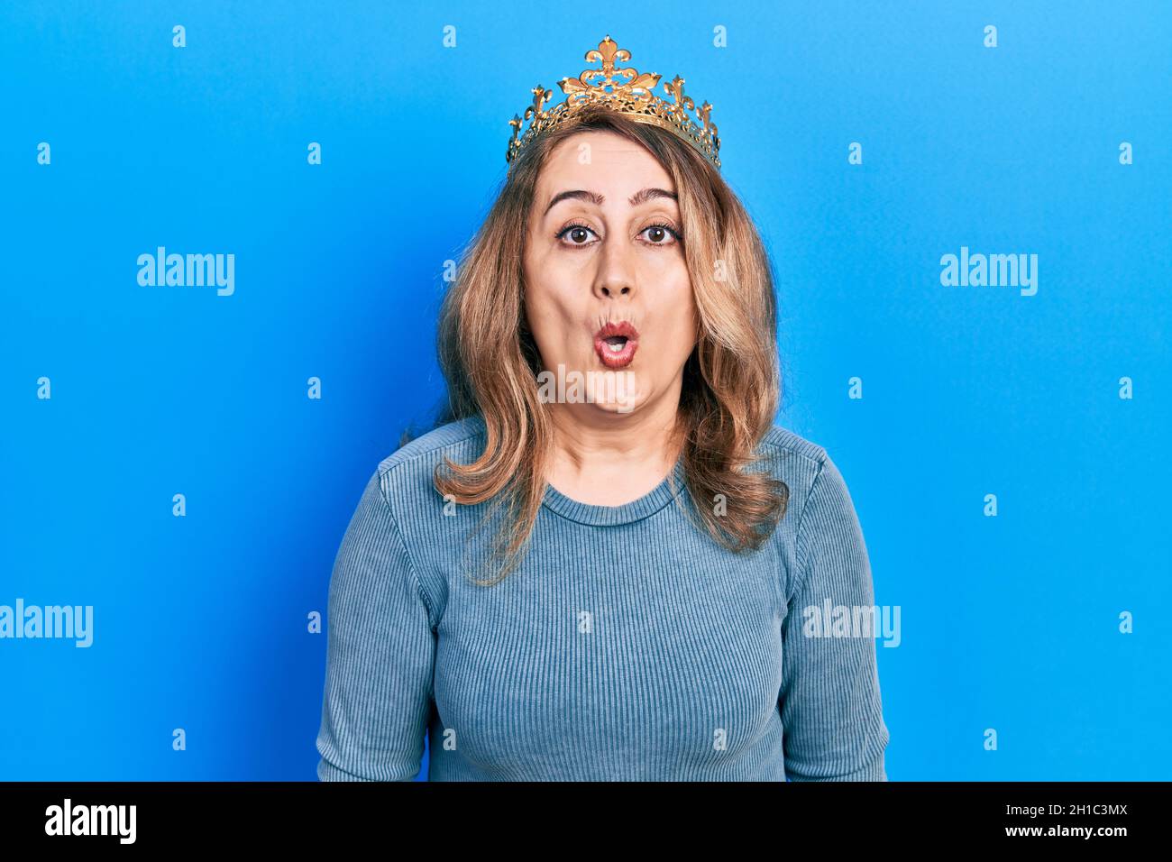 Middle age caucasian woman wearing queen crown afraid and shocked with ...