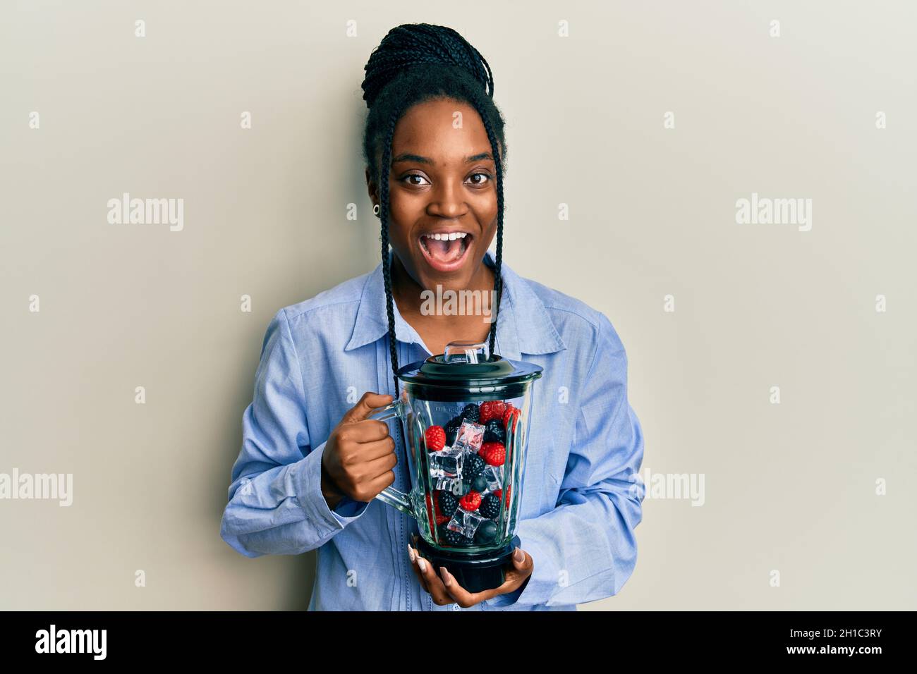 African american woman with braided hair holding food processor mixer ...