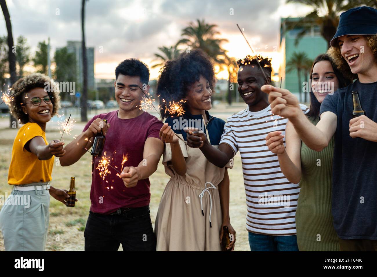 United friends having party together with sparkles while drinking beer ...
