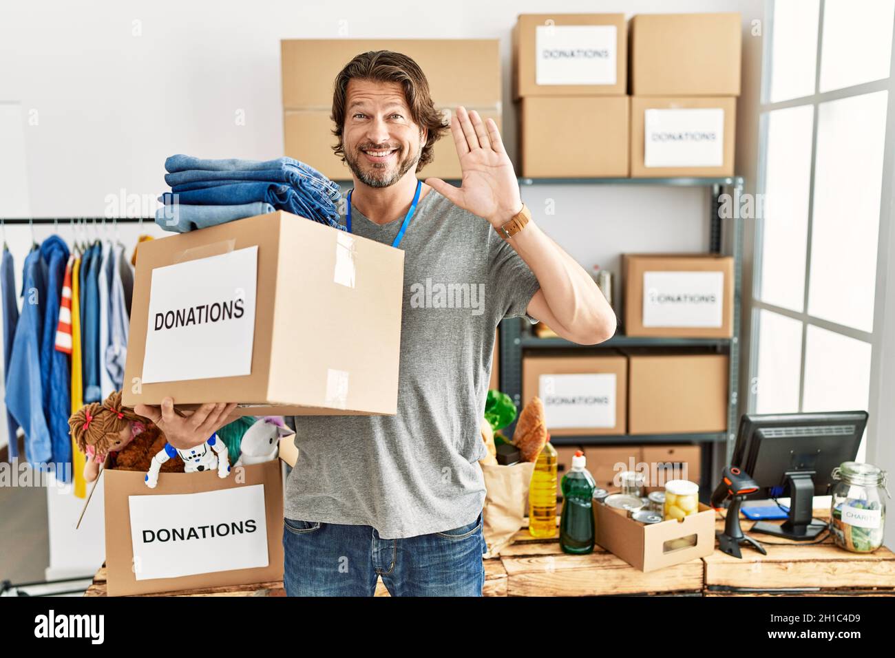 Handsome middle age man holding donations box for charity at volunteer ...