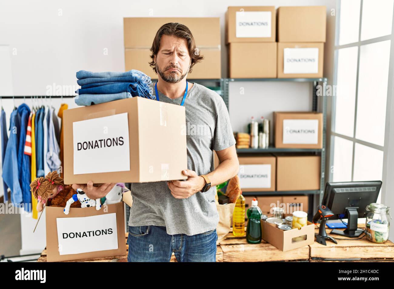 Handsome middle age man holding donations box for charity at volunteer ...