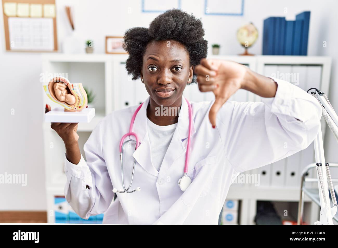 African doctor woman holding anatomical model of female uterus with ...
