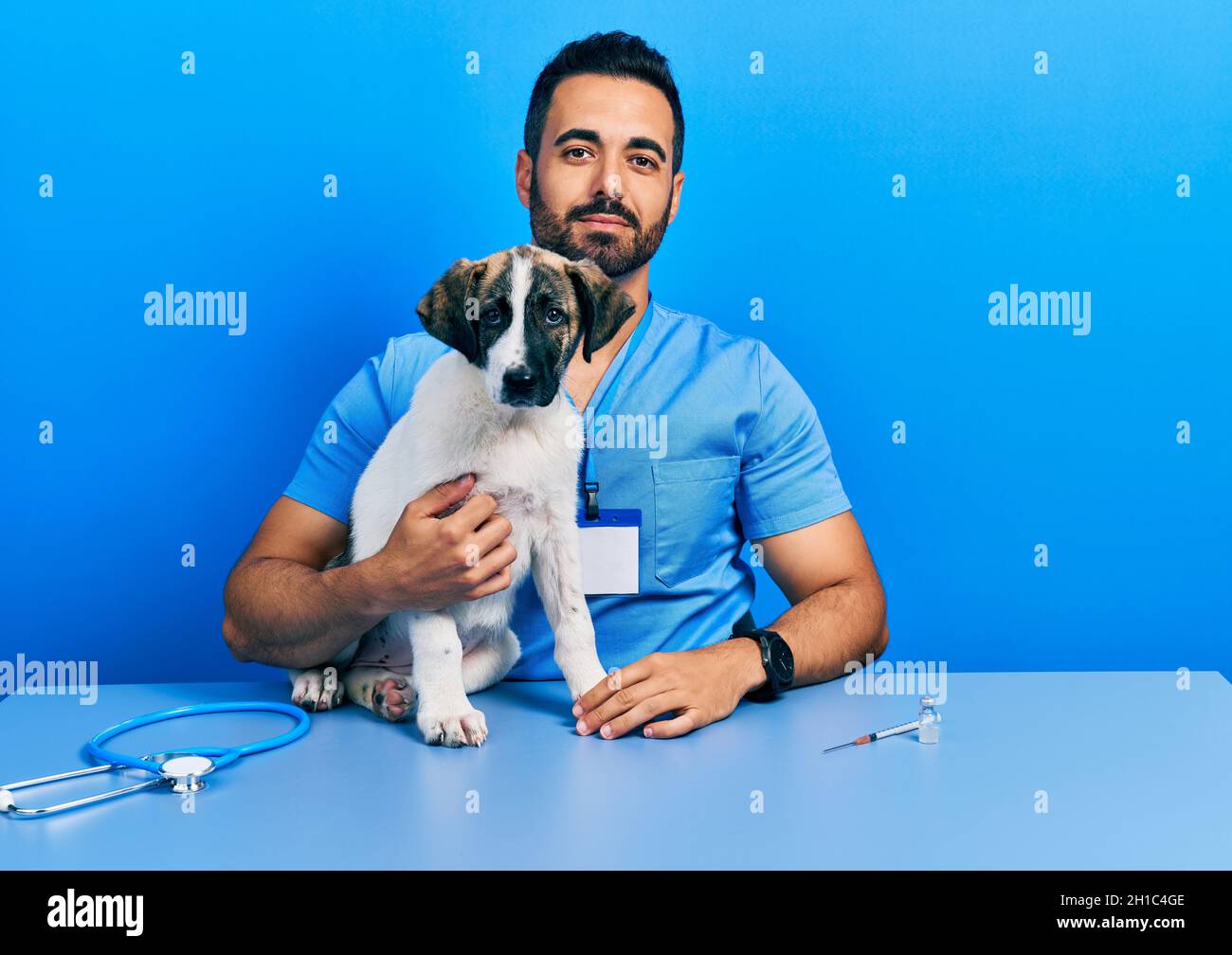 Handsome hispanic veterinary man with beard checking dog health relaxed ...