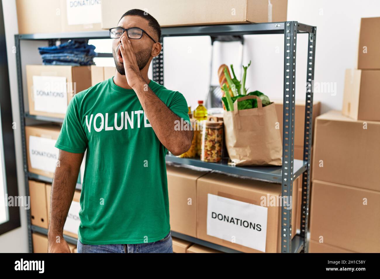 Young indian man volunteer holding donations box shouting and screaming ...