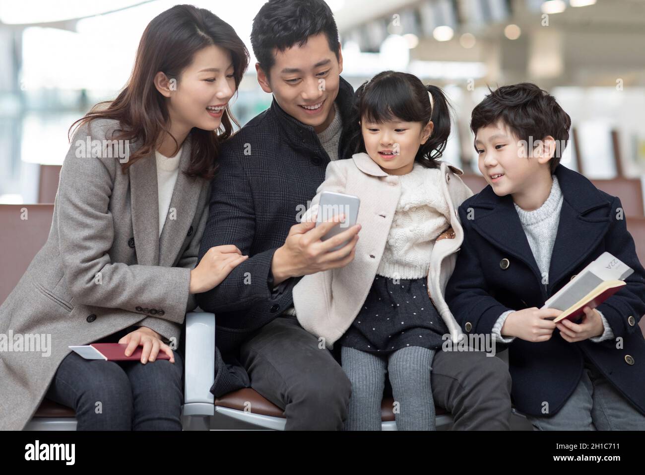 Happy young family waiting for flight at the airport Stock Photo - Alamy