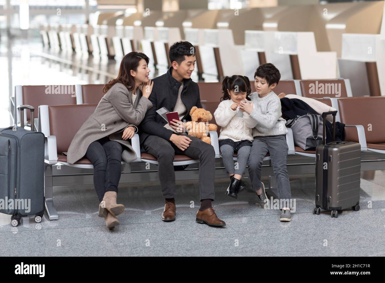 Happy young family waiting for flight at the airport Stock Photo - Alamy