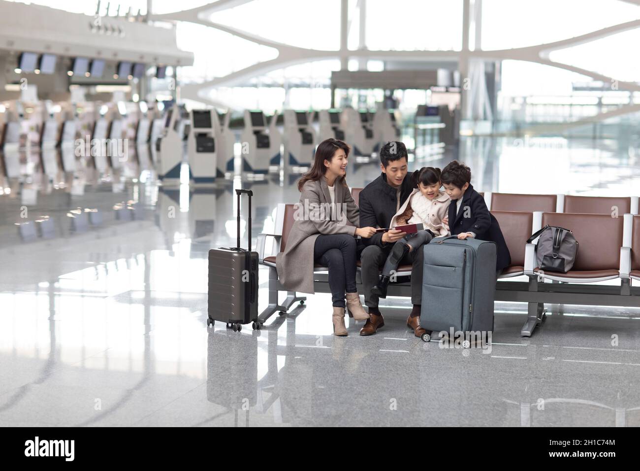 Happy young family waiting for flight at the airport Stock Photo - Alamy