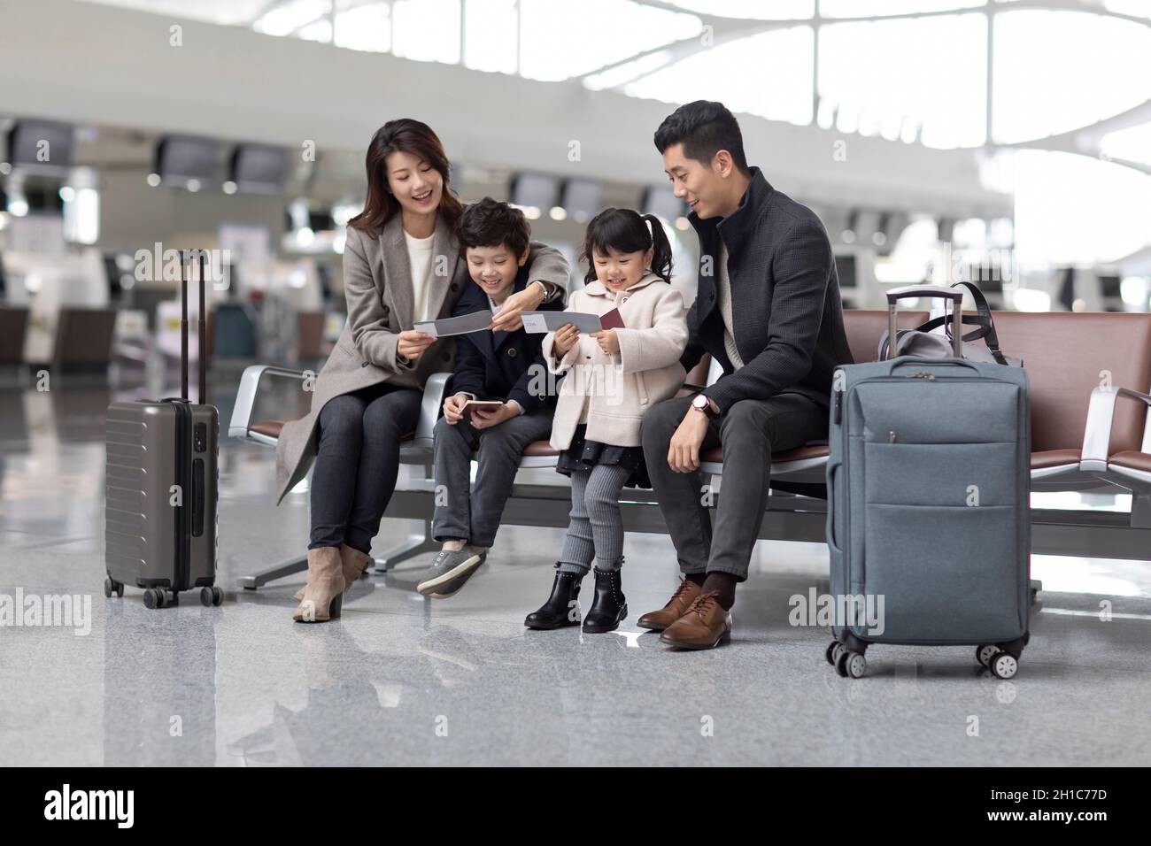 Happy young family waiting for flight at the airport Stock Photo - Alamy