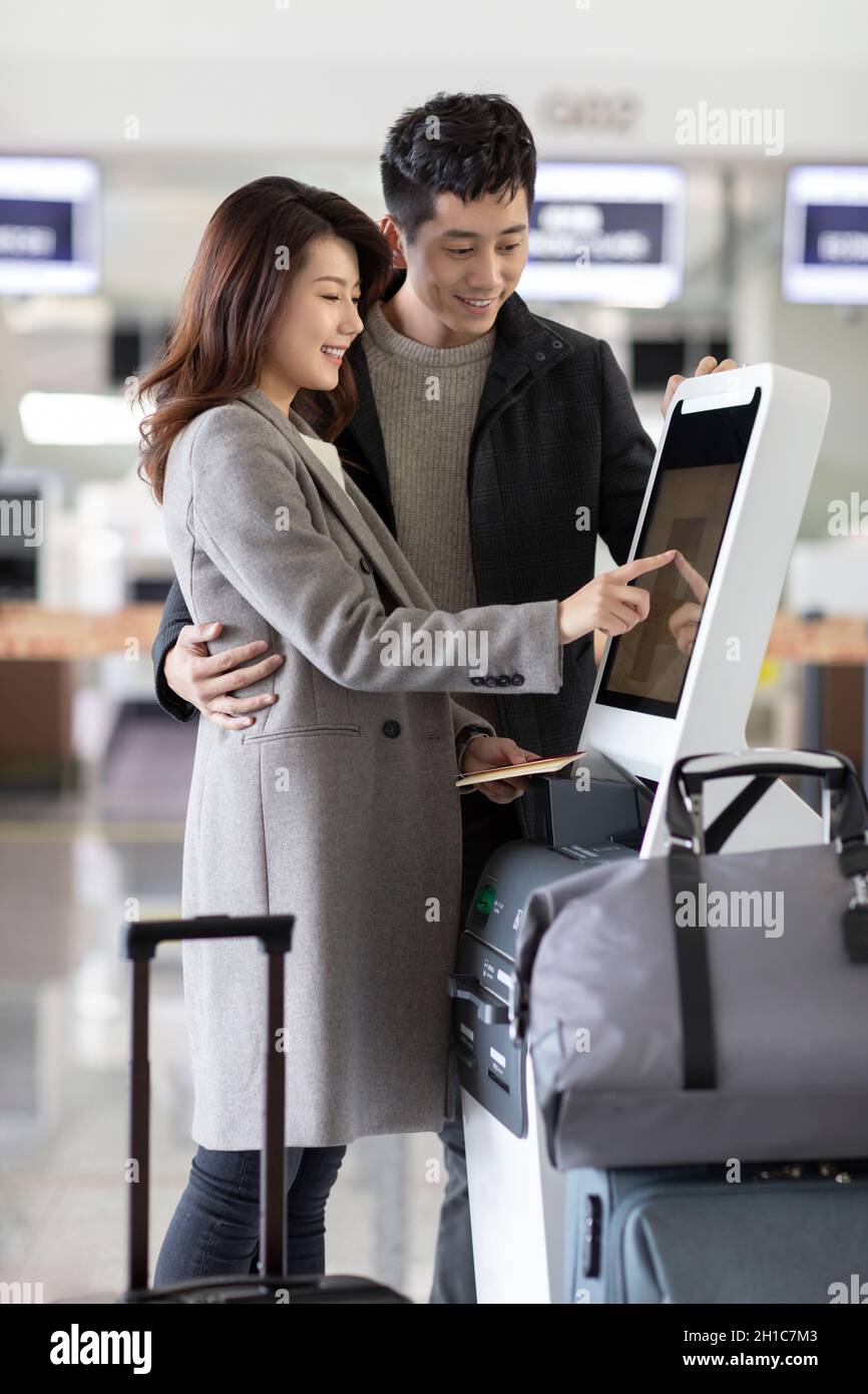 Happy young couple doing self check-in at the airport Stock Photo - Alamy