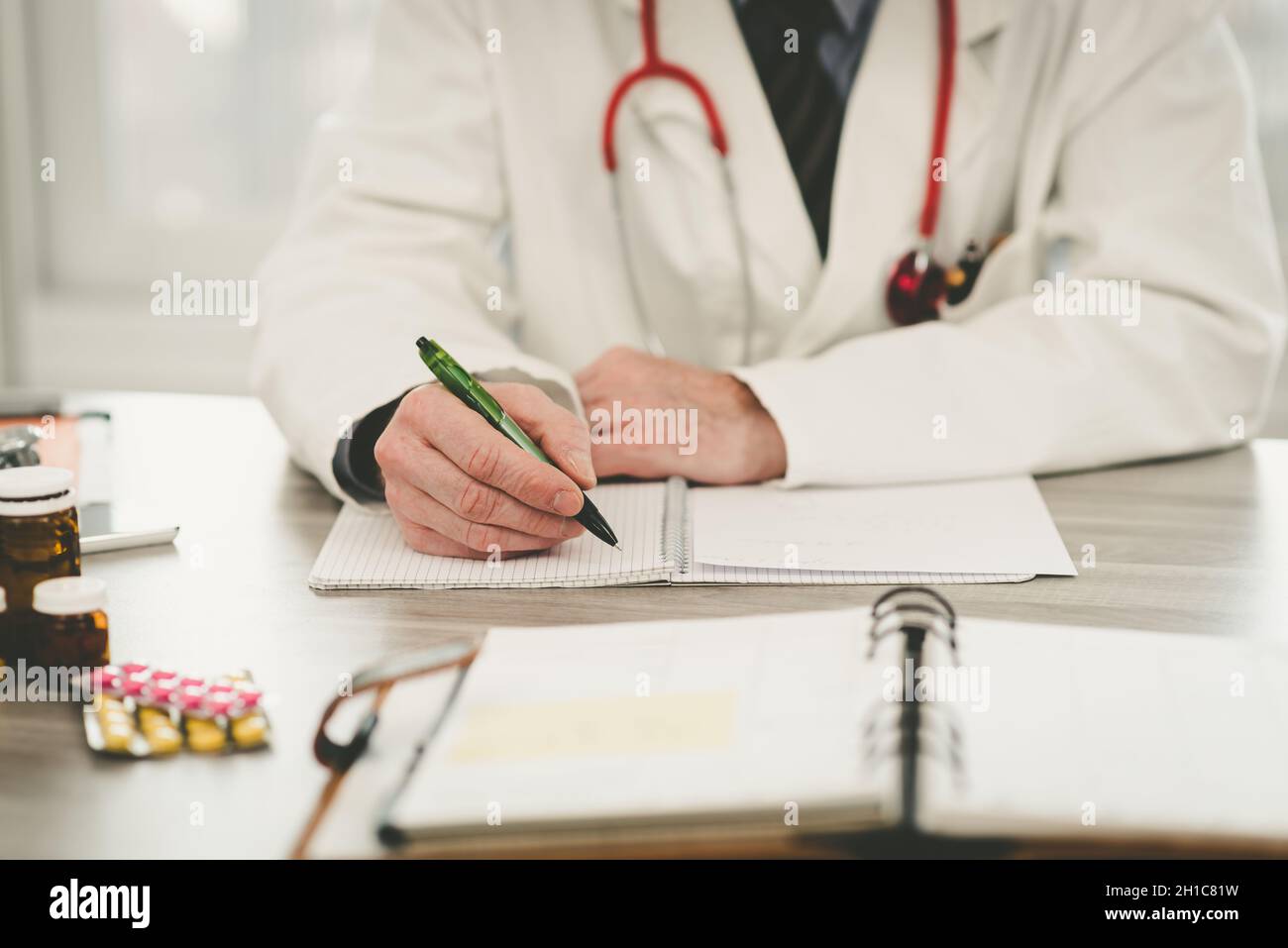Doctor sitting at desk and taking notes Stock Photo - Alamy