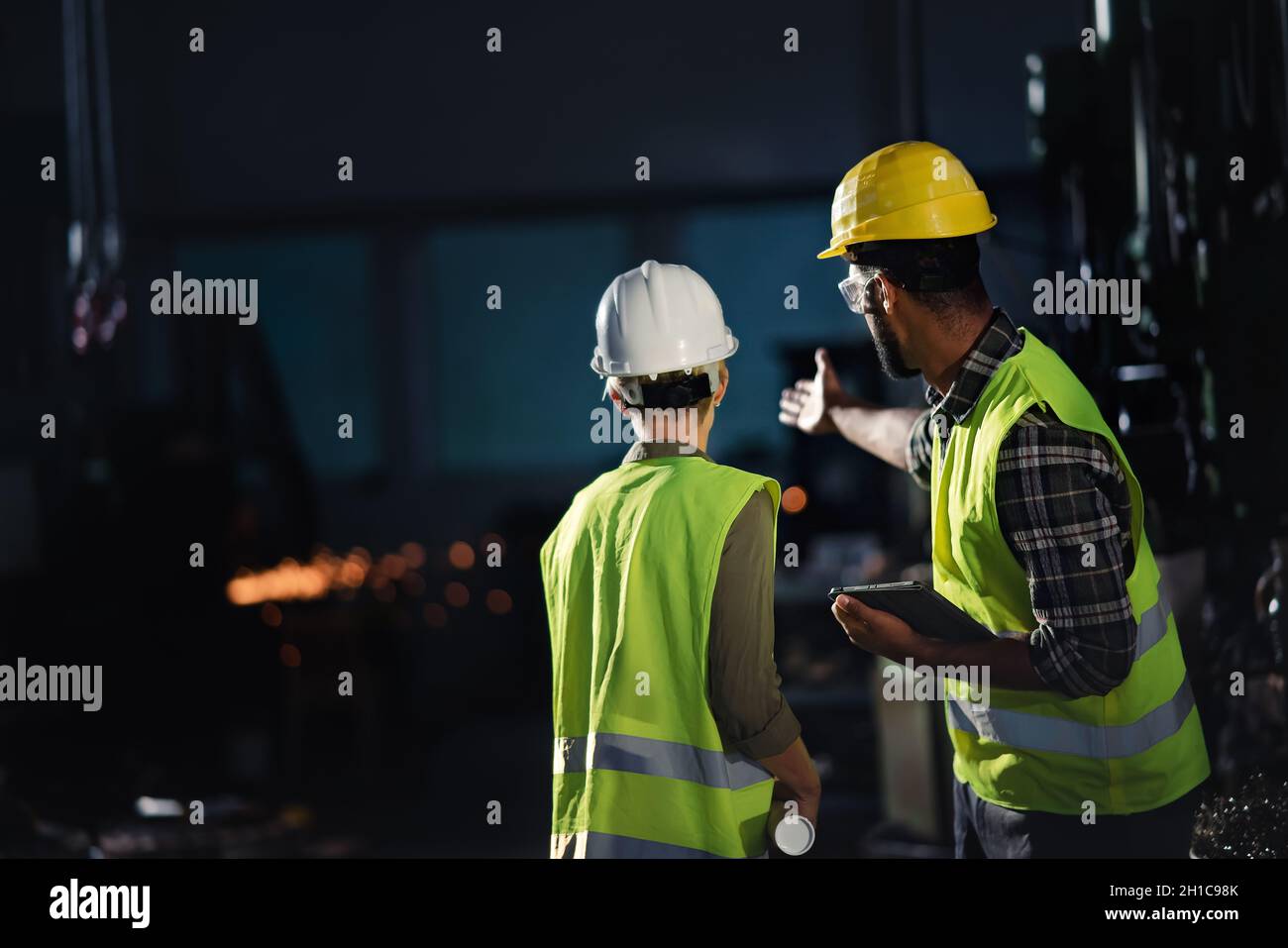 Rear view of industrial inspectors doing a general check up indoors at ...