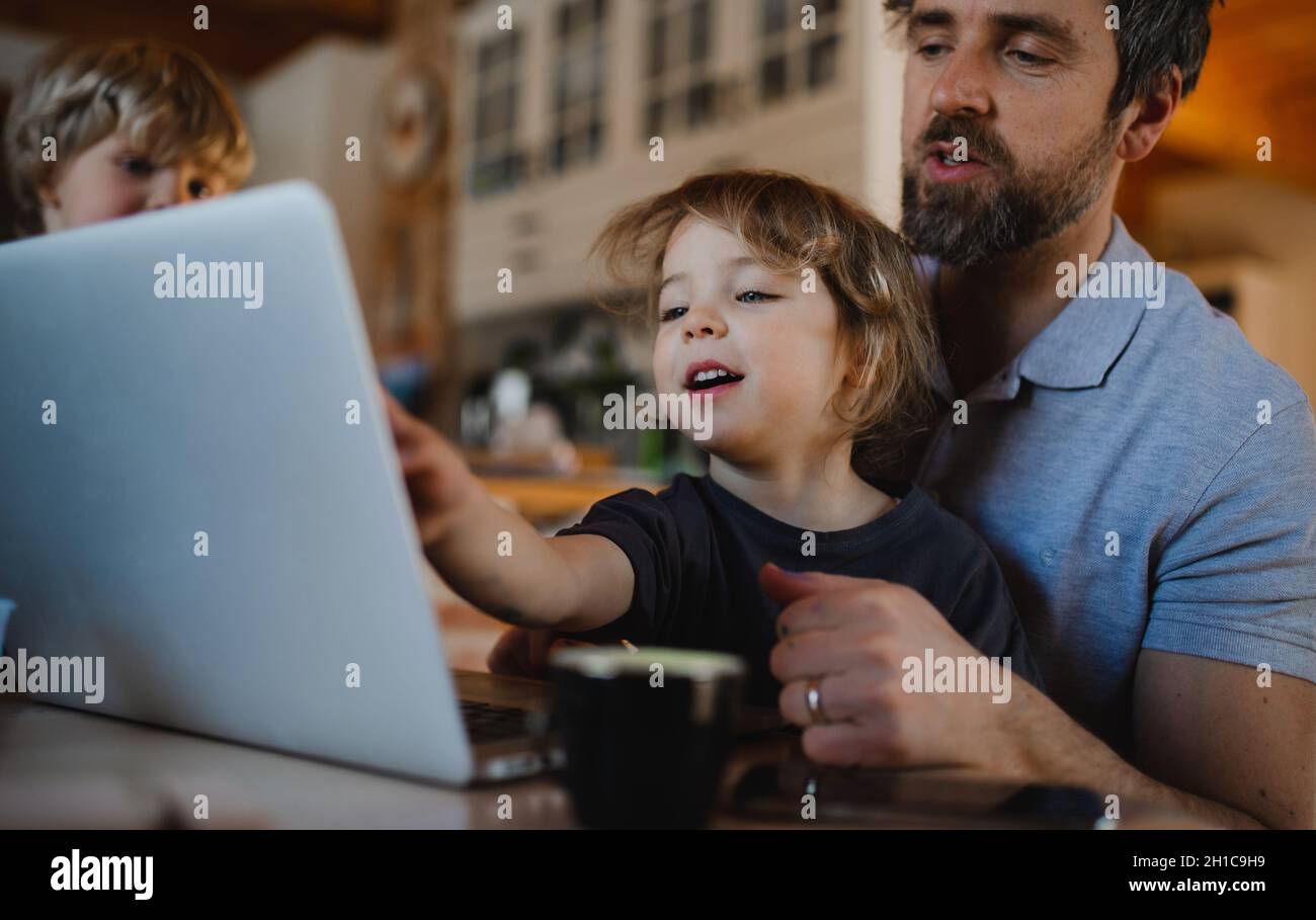Mid adult father with small children working indoors at home, home ...