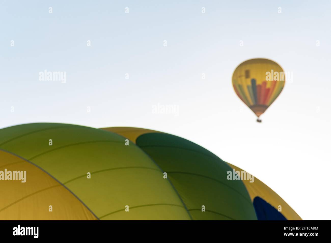 Two hot air balloons flying in the blue sky. One in close detail and ...