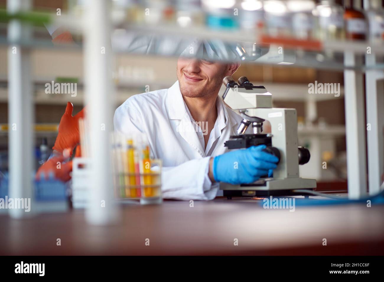 A young male chemistry student enjoying using a microscope in a ...