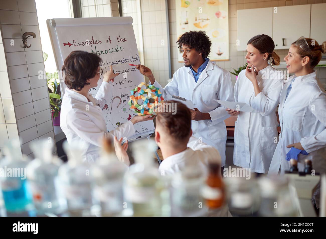 Young chemical students carefully follow a lecturer in the university ...