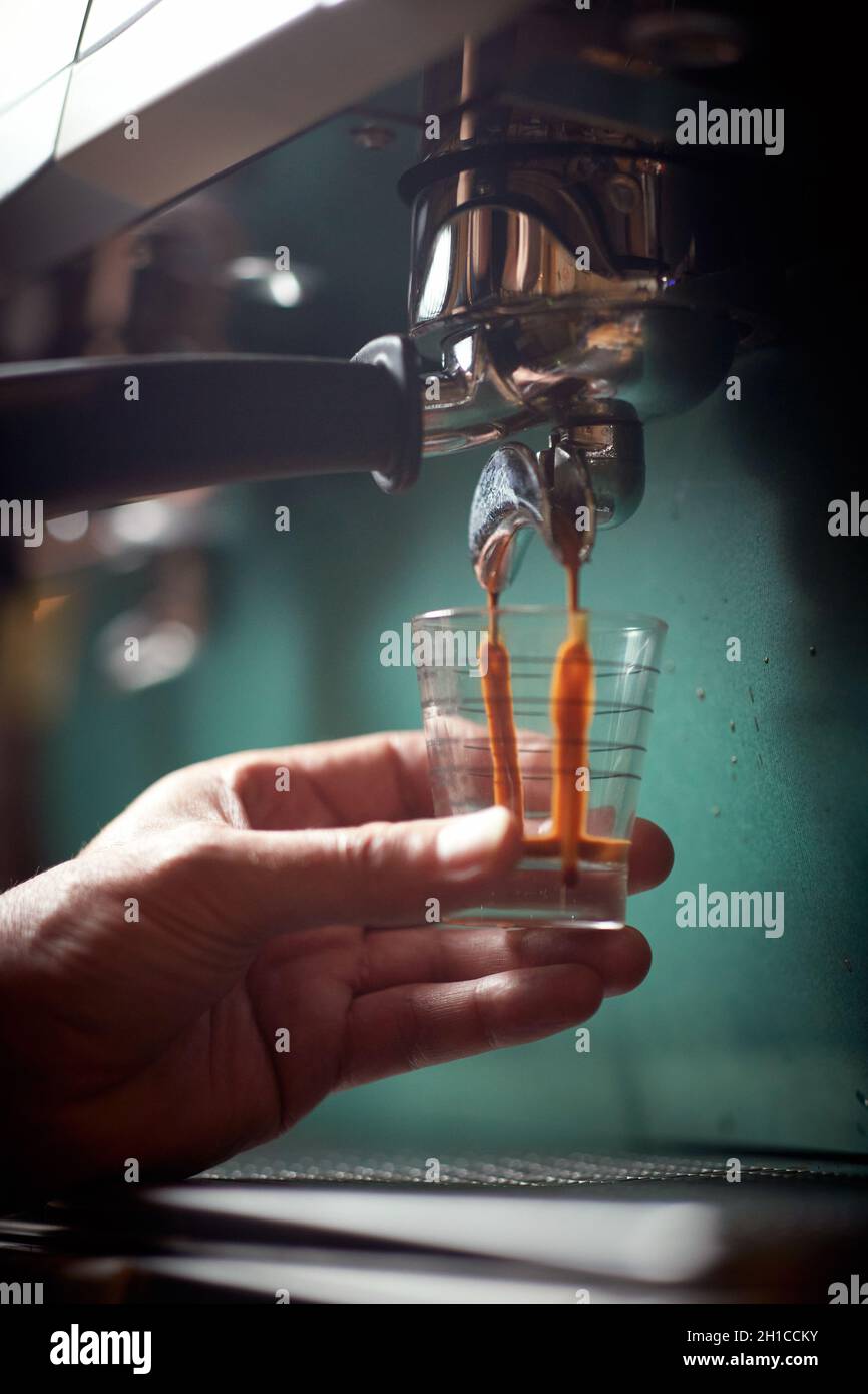 An aromatic and fragrant espresso is pouring into a glass in the ...