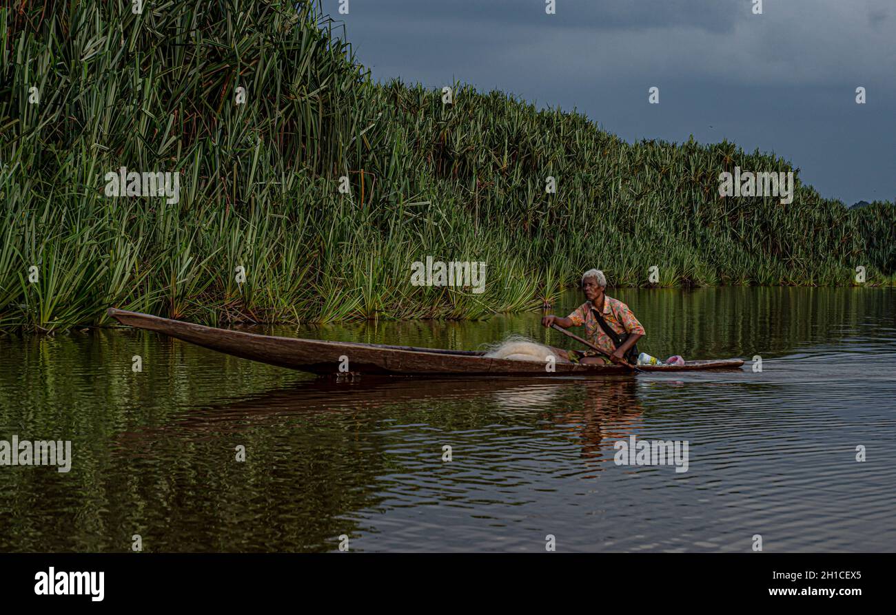 A native male rowing the traditional boat going fishing in the evening ...