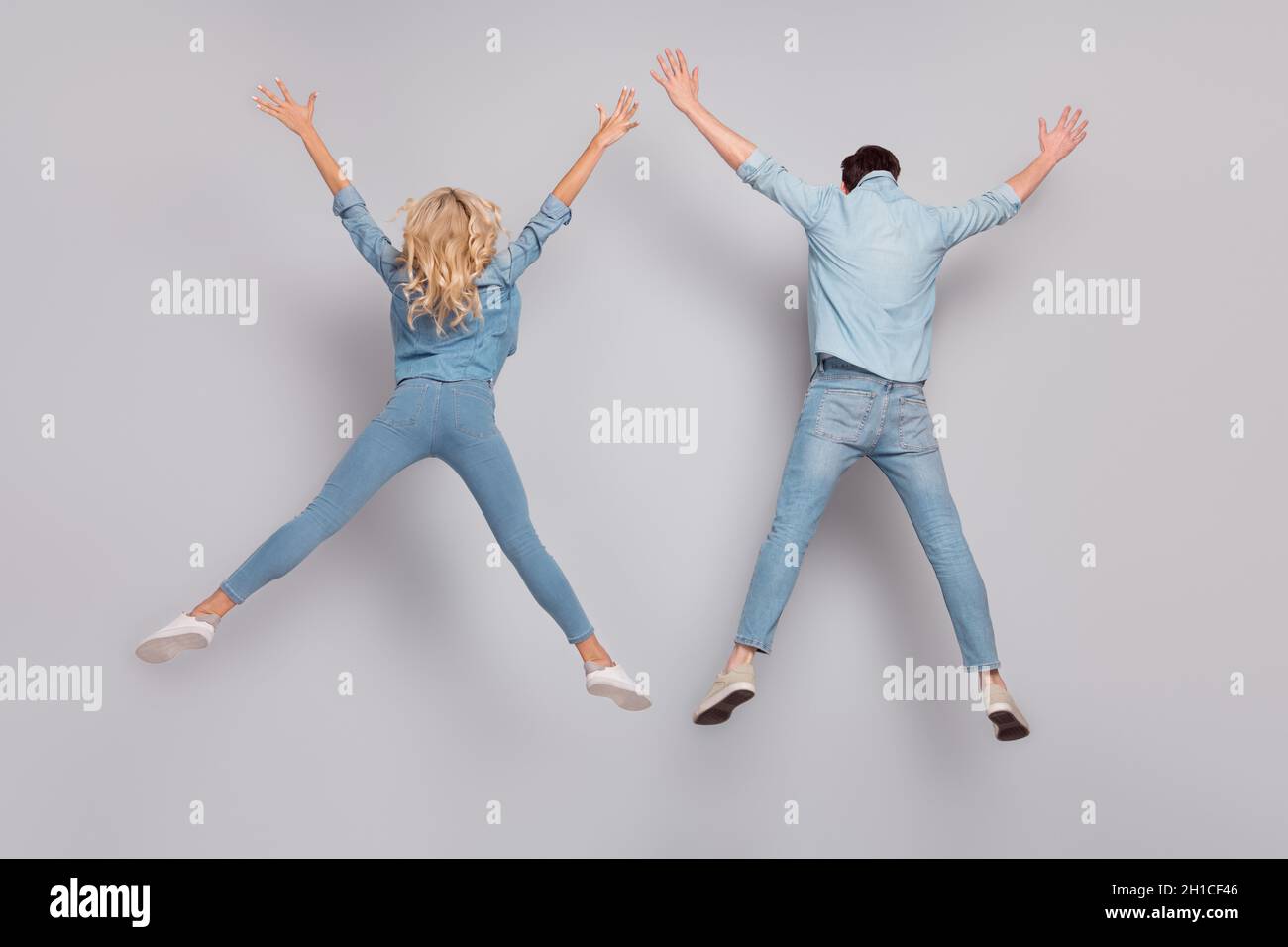 Rear back view photo of couple jump raise hands wear casual jeans ...
