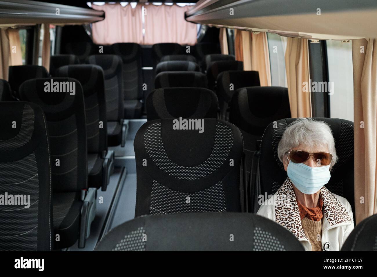 Mature female passenger in casualwear and protective mask sitting on ...