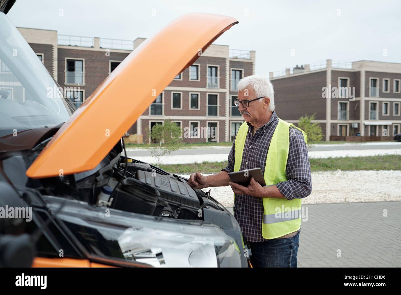 Senior driver of bus looking at engine while checking it before driving ...