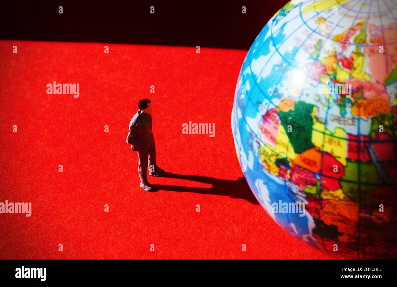 Miniature Man observing the planet earth in a red background Stock ...