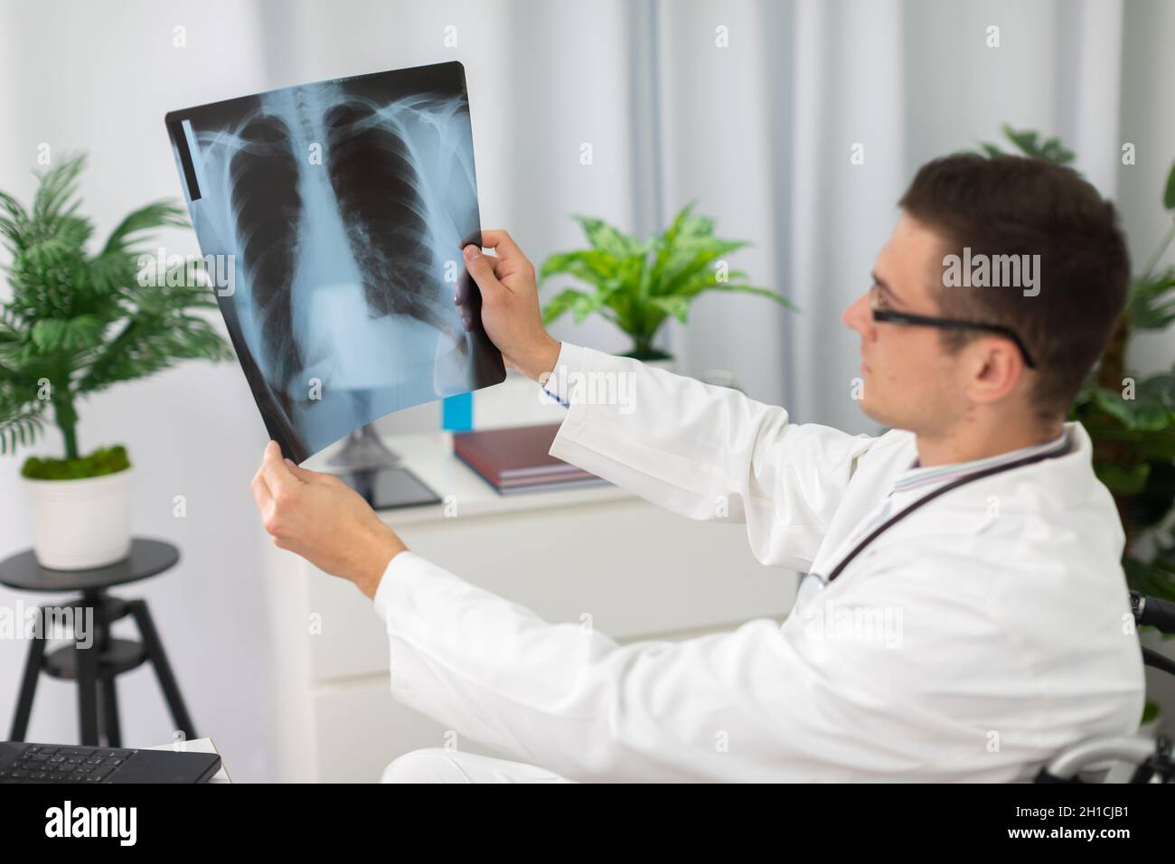 A pulmonologist in his medical office initially checks his patient's ...