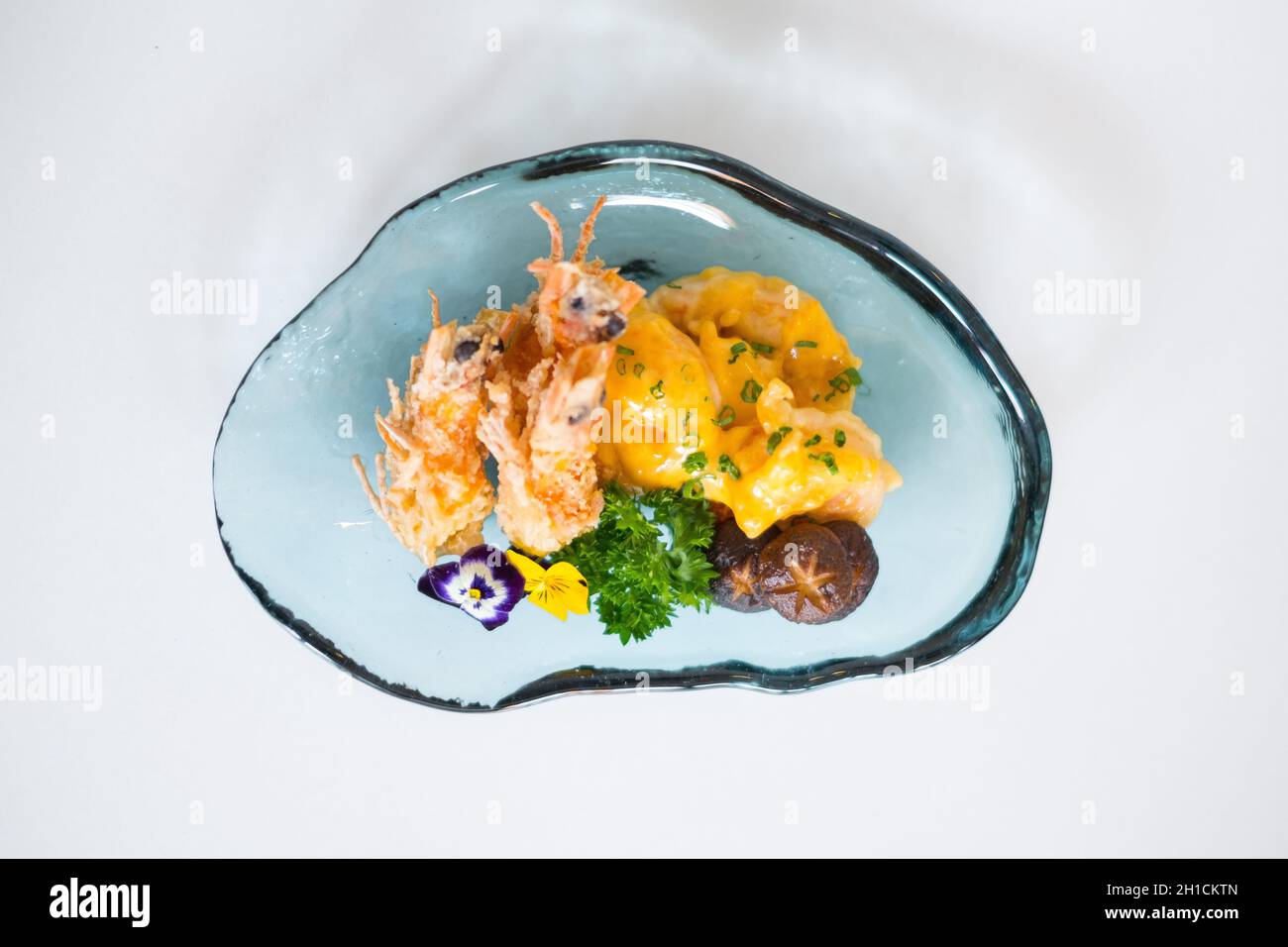 Two shrimps in batter with sauce and mushrooms on the blue designed ...