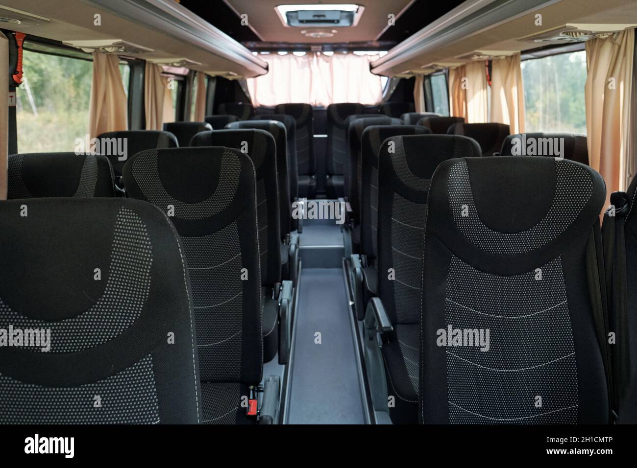 Two rows of grey and balck double seats and long aisle between them ...