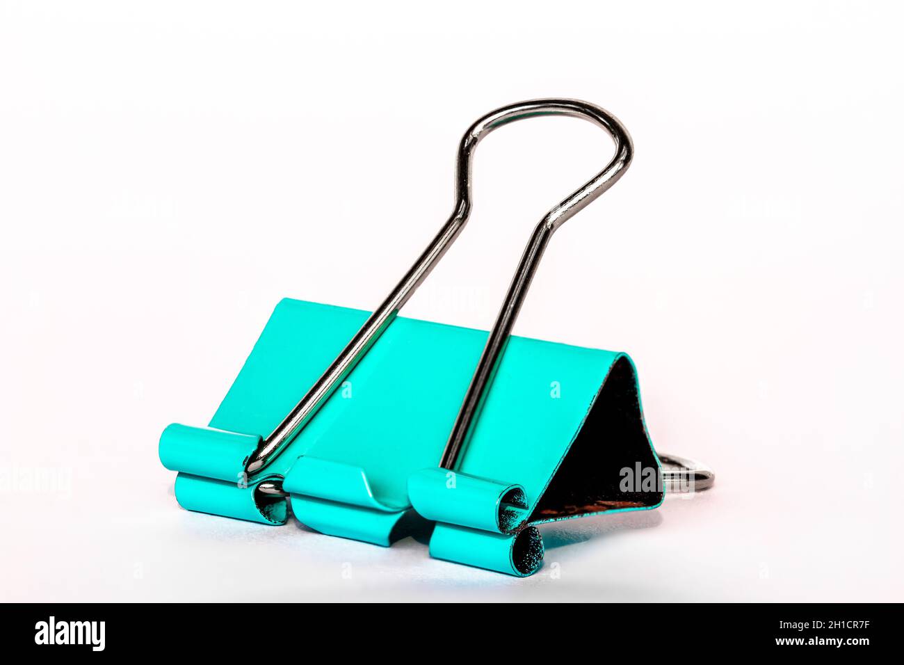 One blue paper clip made of metal, isolated with a white background ...