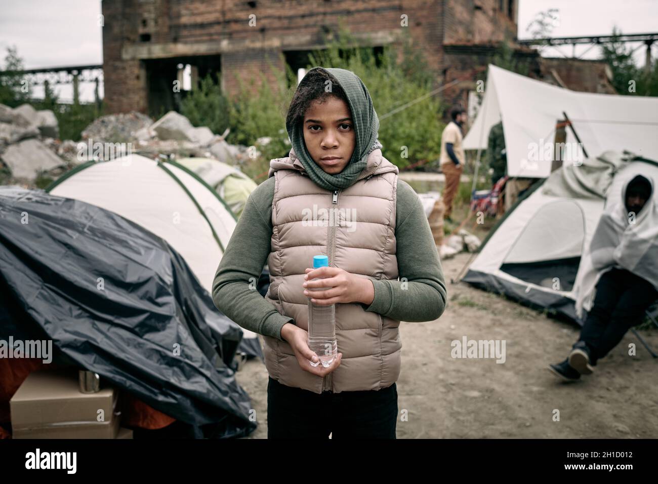Cute girl with bottle of water standing in front of camera against ...