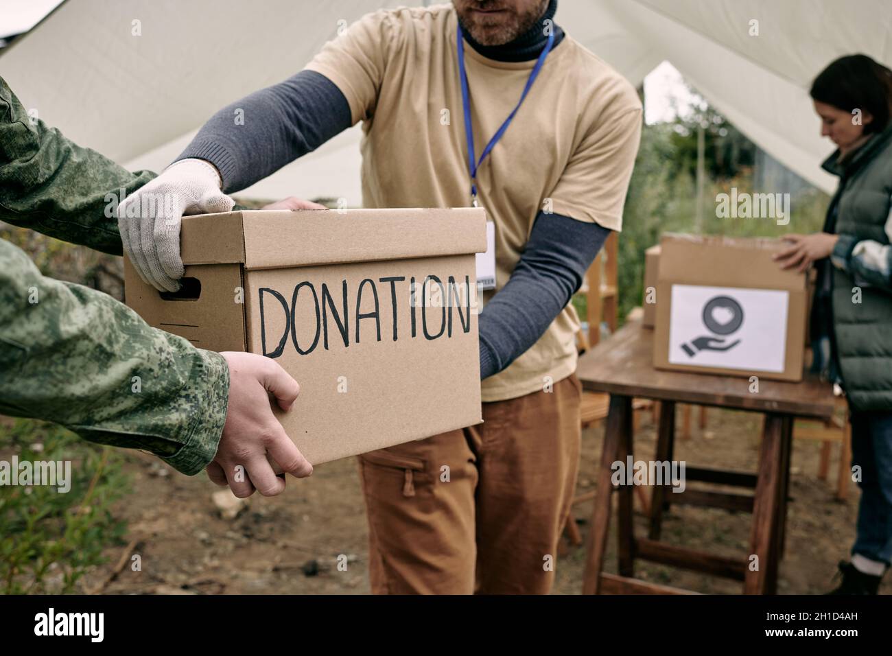 Young man in gloves taking package with donation against female ...