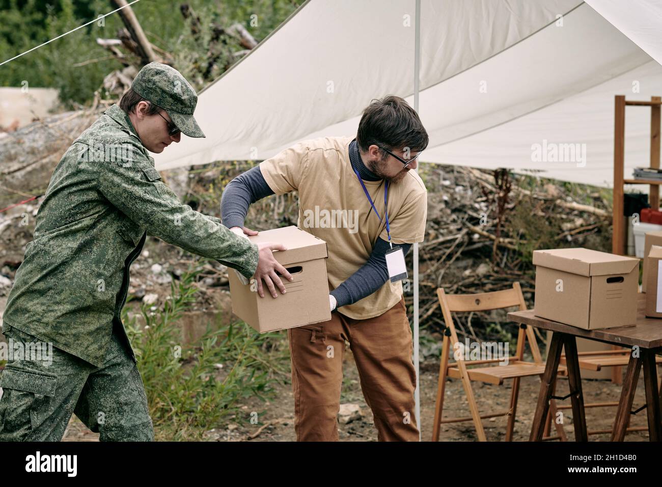 Two young men delivering boxes with donation for homeless people or ...
