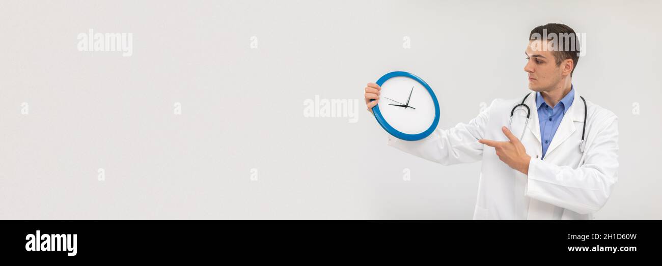 The doctor holds a wall clock in his hands measuring the daily time ...