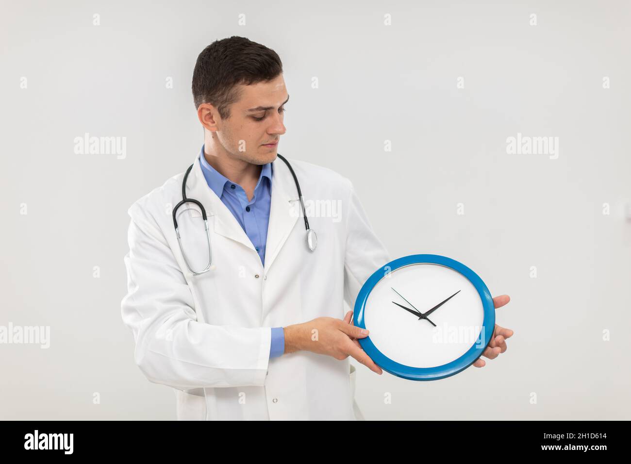 The doctor holds in his hands a wall clock measuring the daily time ...