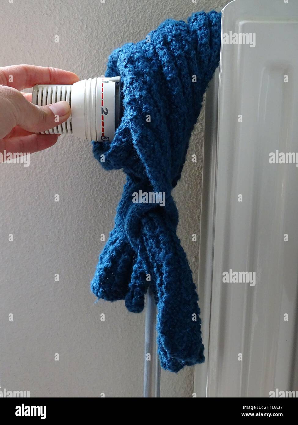 a blue scarf around the radiator and a hand turns the radiator on cold ...