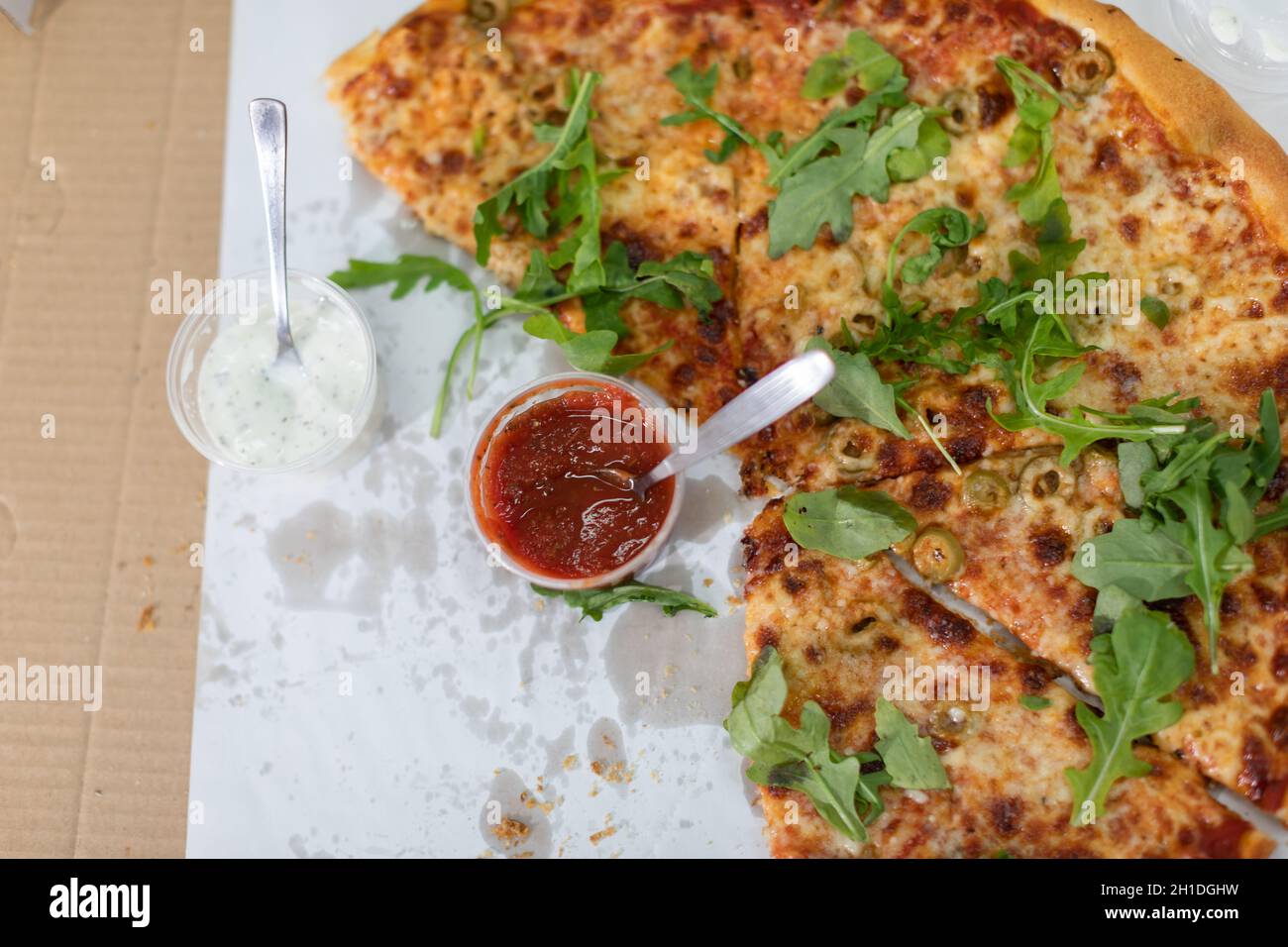 Unfinished pizza with arugula leaves at a college party Stock Photo - Alamy