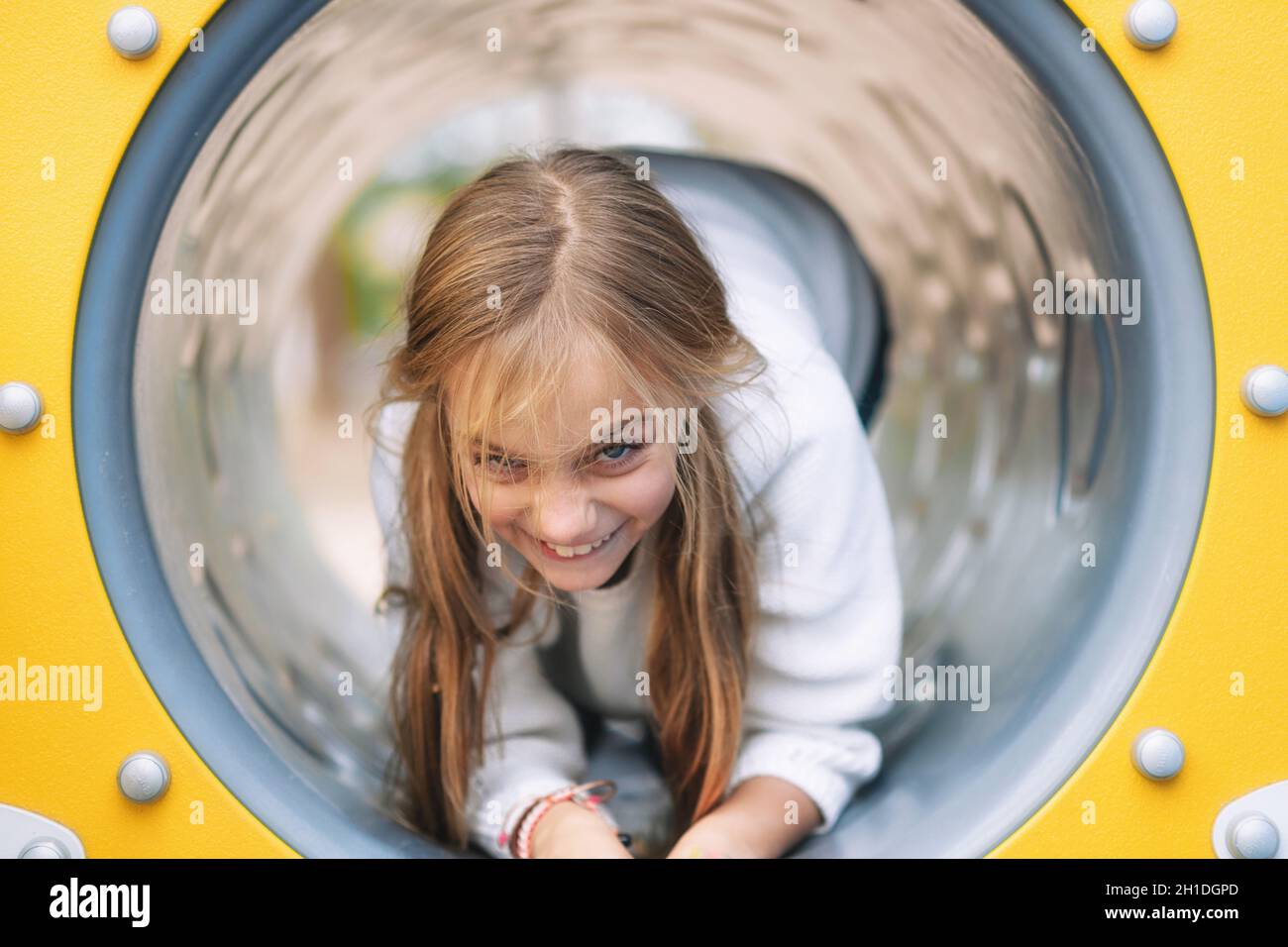 Pretty, little girl, having fun, crawling on pipe on children ...