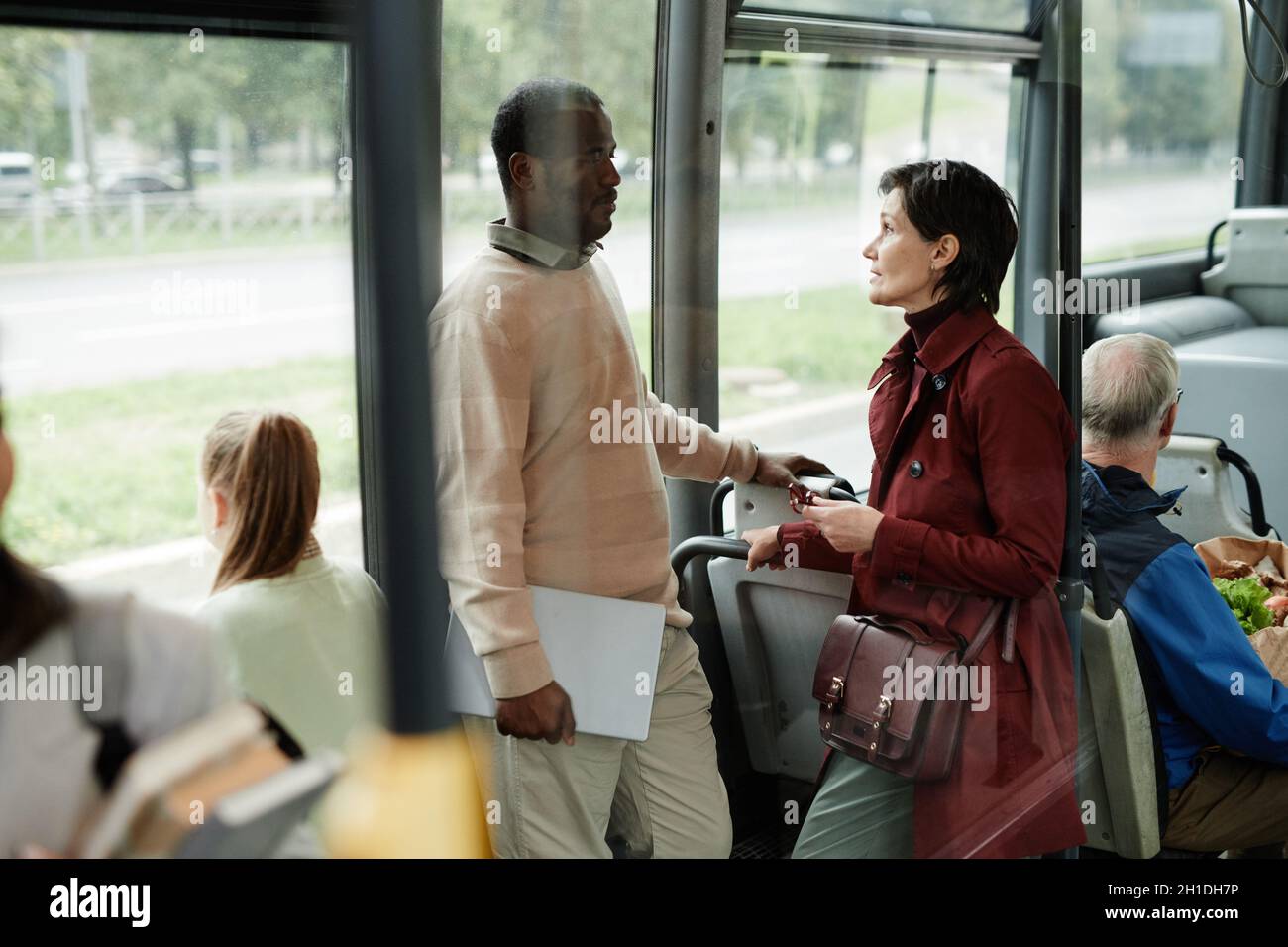 Side view portrait of two people talking while standing on bus and ...
