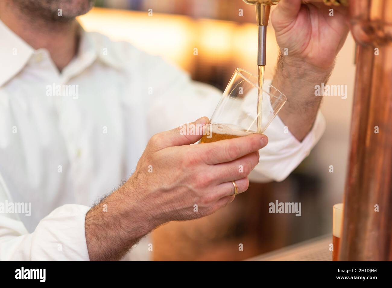 Pouring beer for client. Bartender pouring beer while standing at the ...