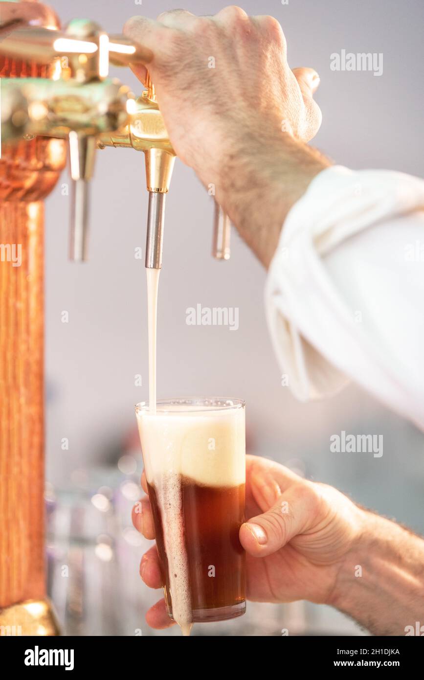Pouring beer for client. Bartender pouring beer while standing at the ...