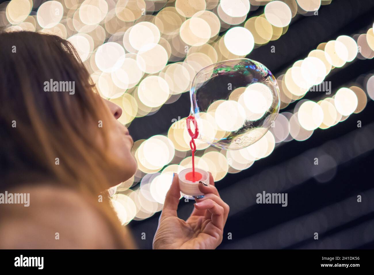 Woman having fun making soap bubbles at night party Stock Photo - Alamy