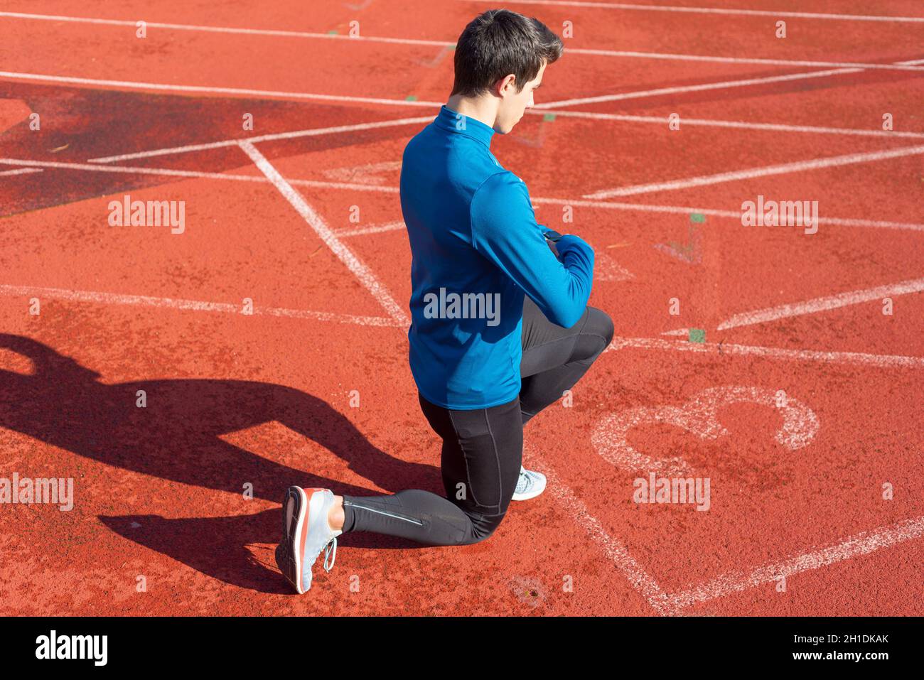 Man athlete on the starting line of a running track at the stadium ...