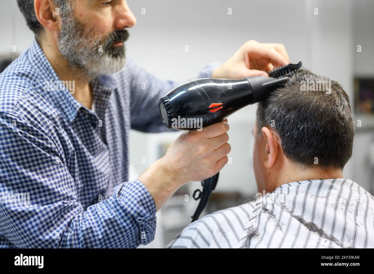 Barber trimming hair of old man at barber shop Stock Photo - Alamy