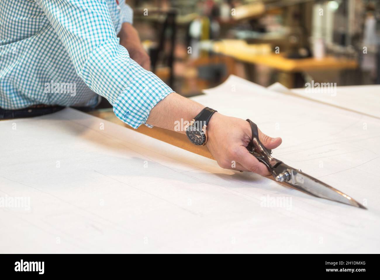 Tailor cutting out the marked pattern on fabric with large scissors on ...