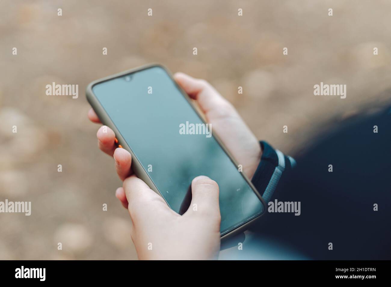 Child hands uses smartphone in summer park, looking at screen of ...