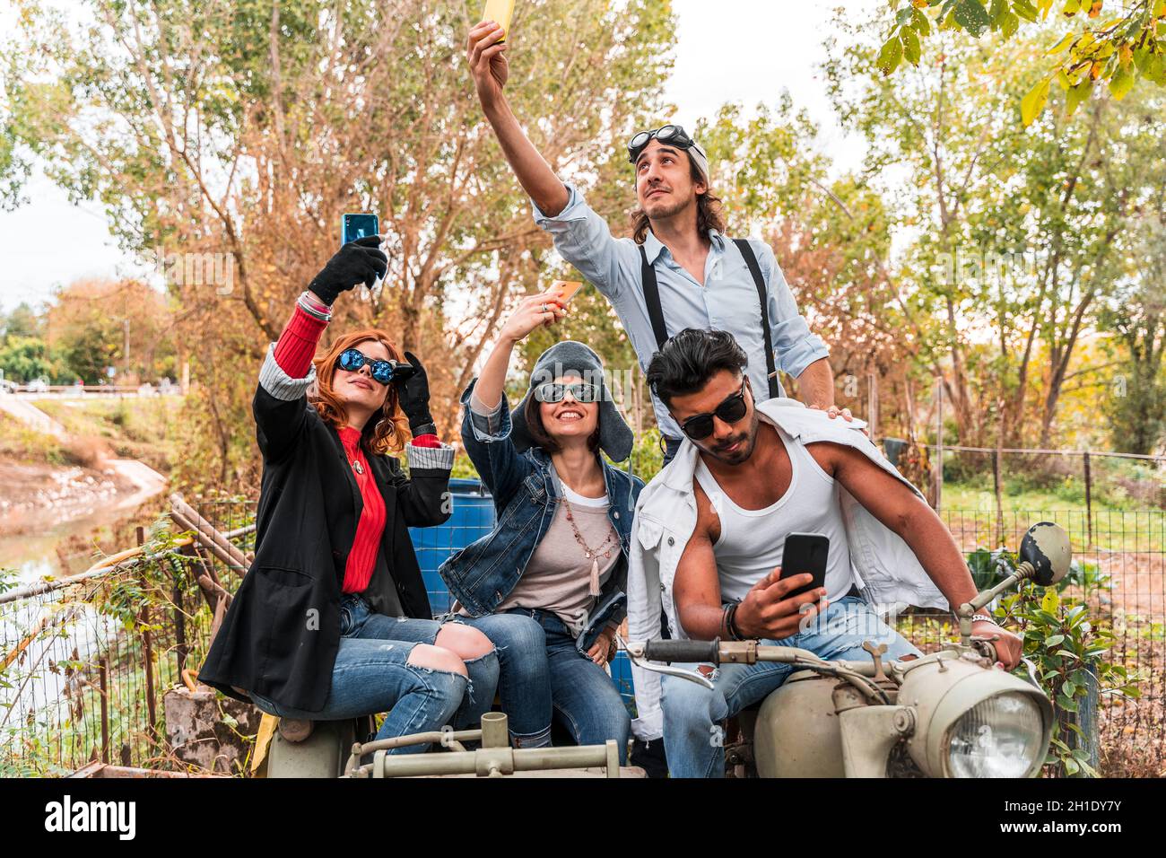 group of best friends take a selfie riding a vintage motorcycle with ...