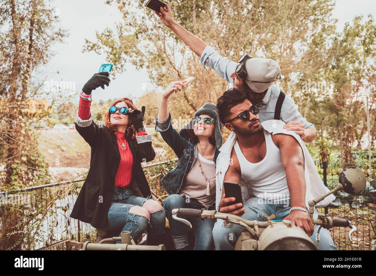 group of best friends take a selfie riding a vintage motorcycle with ...