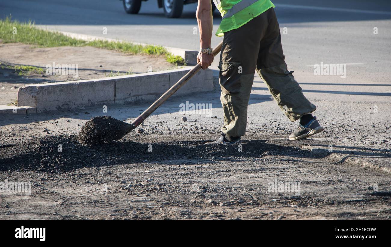 Workers repair the road surface and asphalt the street. People in ...