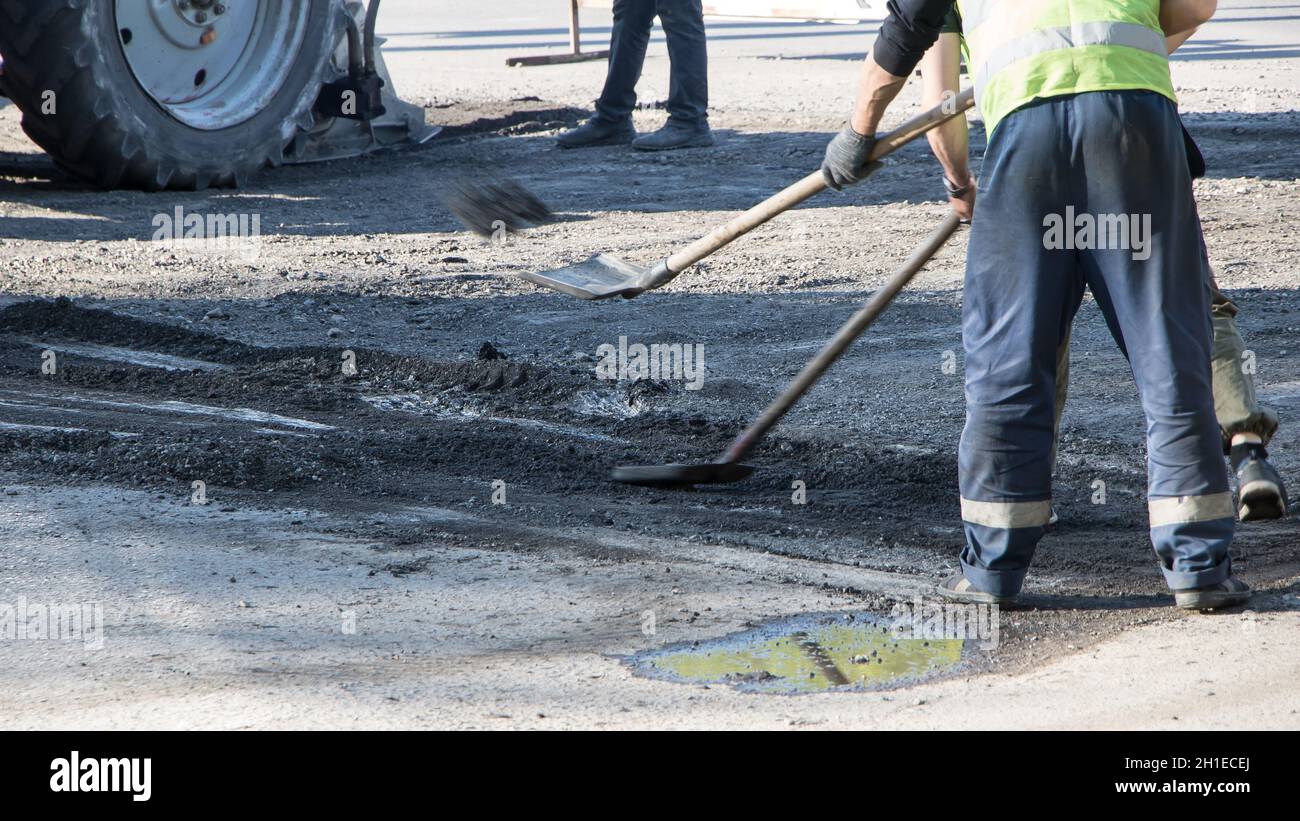 Road works. Workers repair the road surface and asphalt the street ...