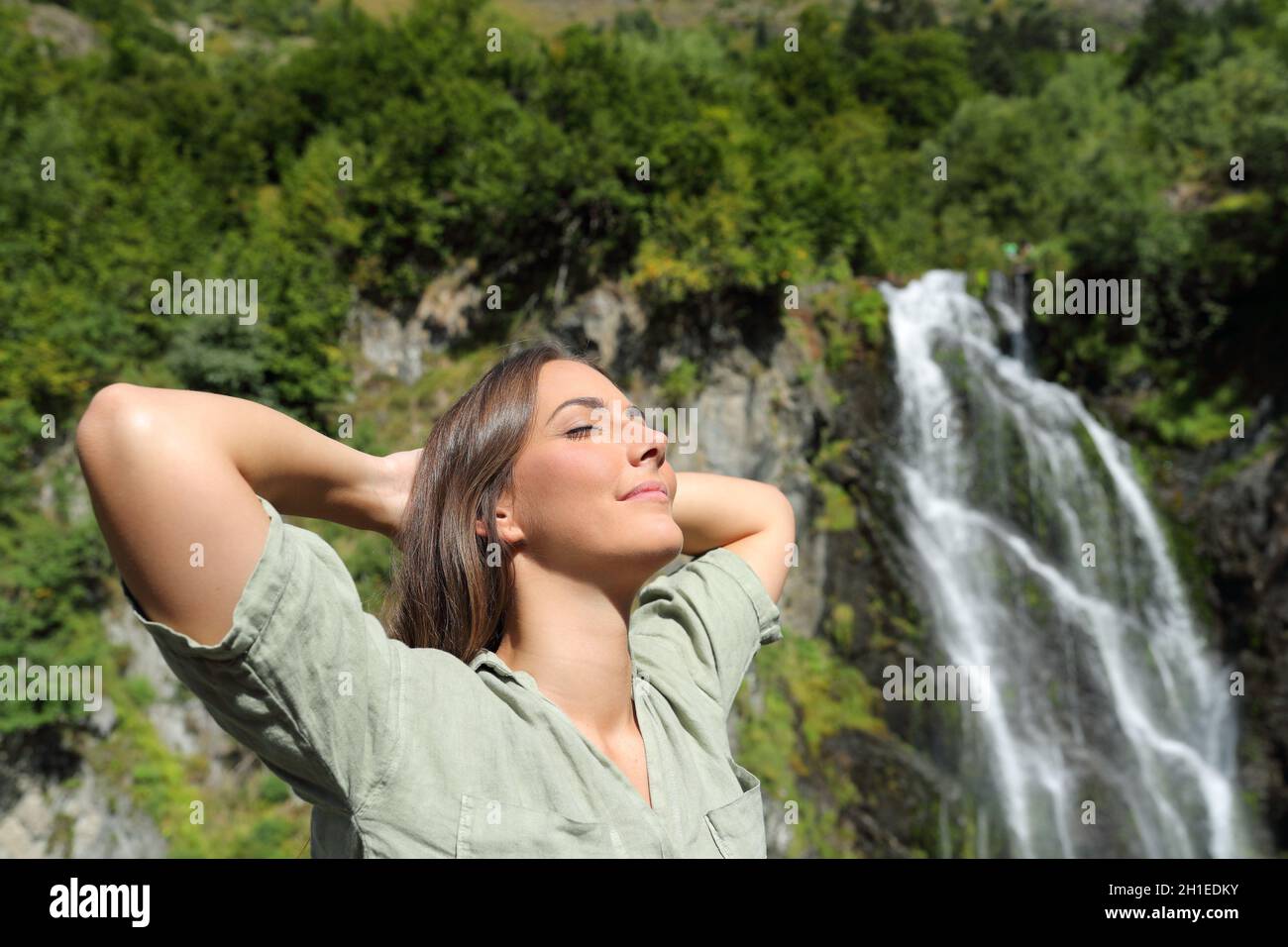 Happy woman breathing fresh air and resting in a waterfall in the ...